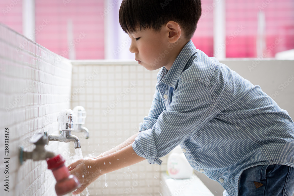 An adorable little asian boy washing his hands before lunch at the wash ...