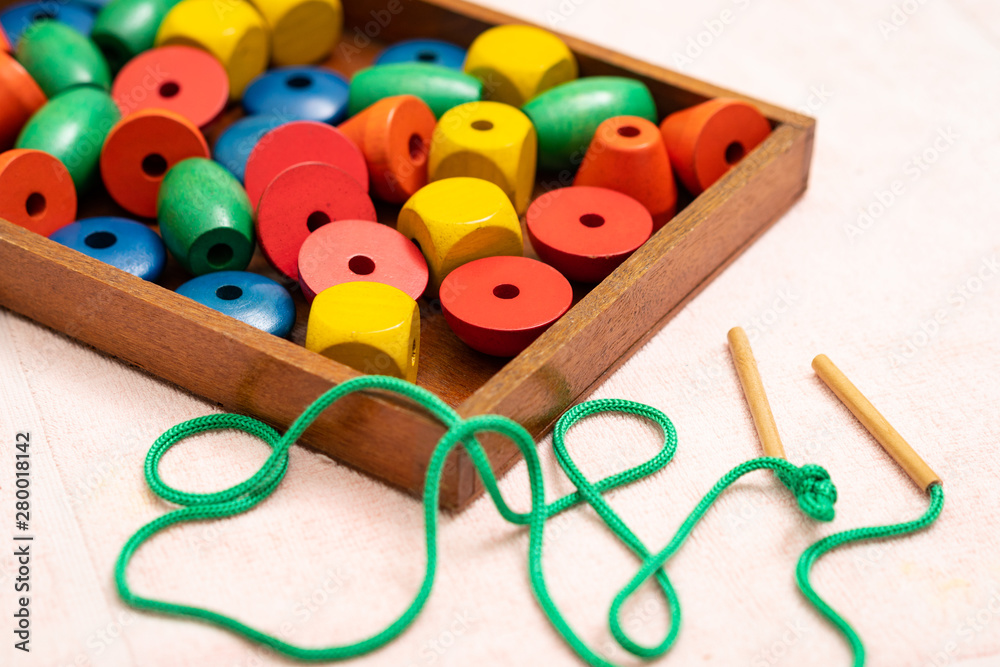 Top view closeup of colorful wooden beads, needle in the tray ...