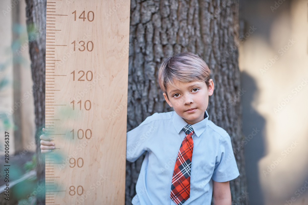 Schoolboy with big ruler standing on wooden background. Farewell Bell ...