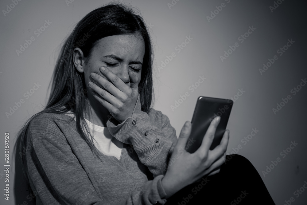 Foto de Depressed teenager girl on mobile phone victim of cyberbullying ...