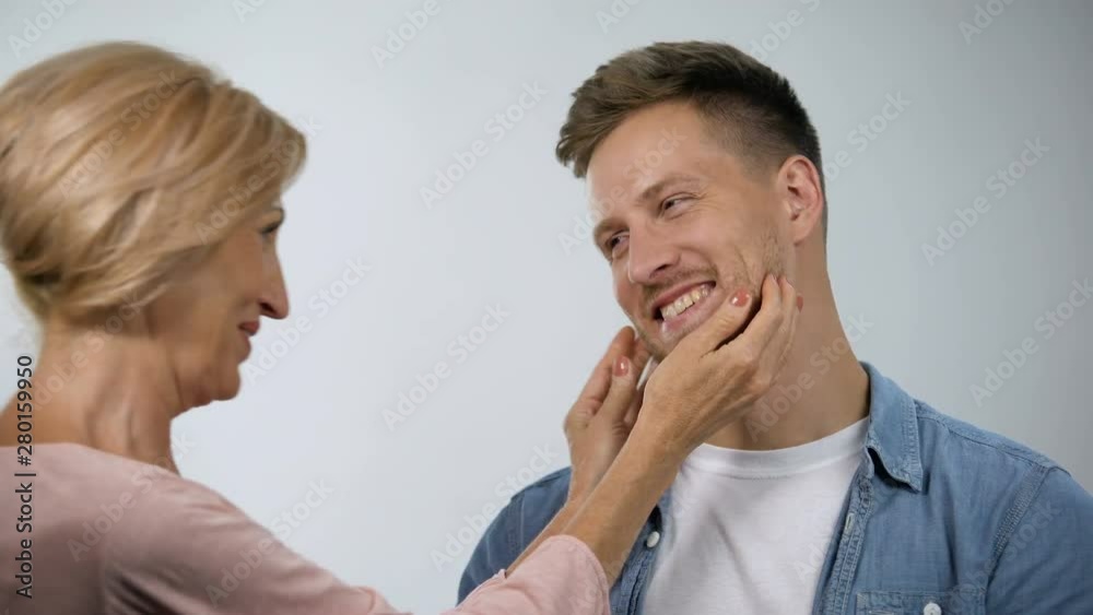 Mother pinching cheeks to infantile adult son under mom overprotection ...