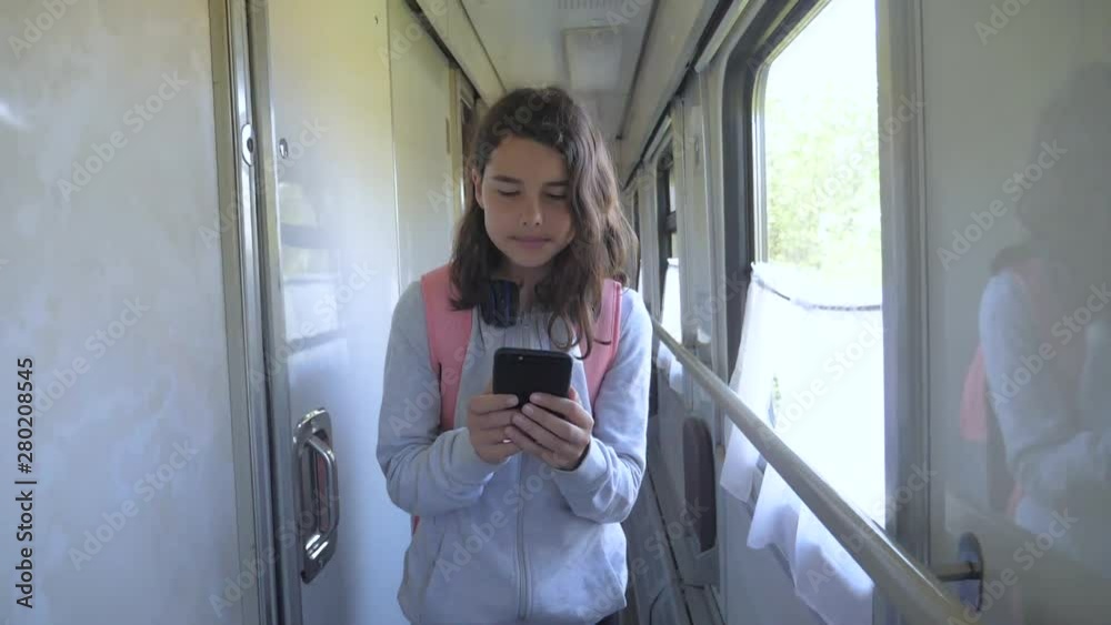 teen girl walks on a train compartment car with a backpack and a ...
