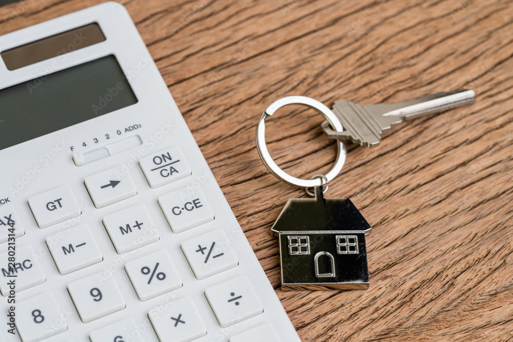 Home key with house keyring or keychain with white calculator on wooden ...