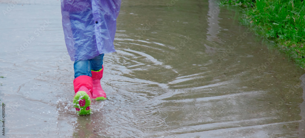 Little child girl jumping on puddles in rubber boots. Happy childhood ...