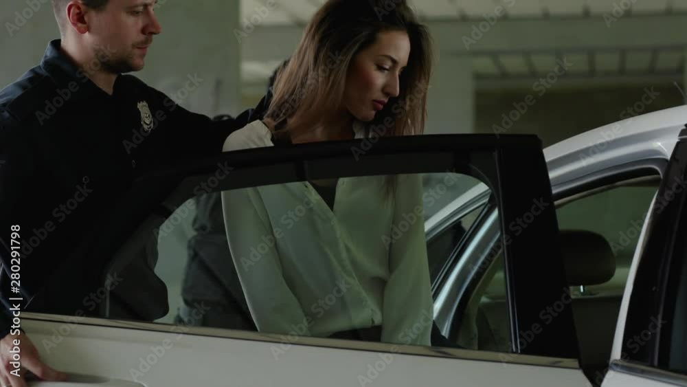 Close up young woman arrested by police officers and handcuffed sitting ...