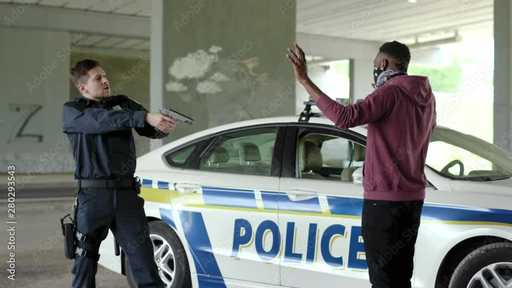 Angry policeman with a pistol standing with a robber in handcuffs ...