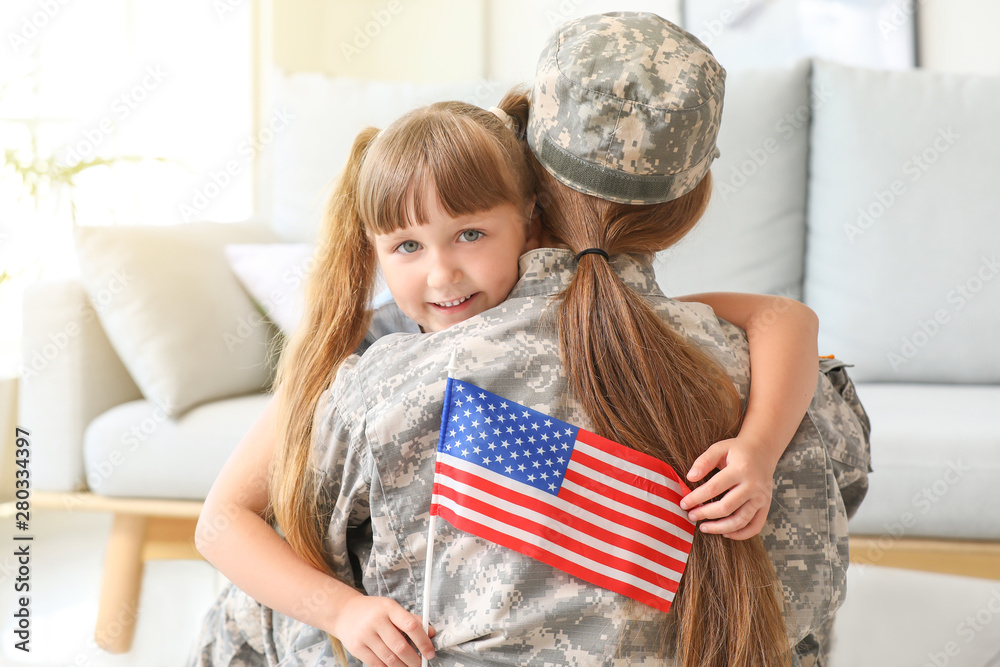 Happy female soldier of USA army hugging her little daughter at home ...
