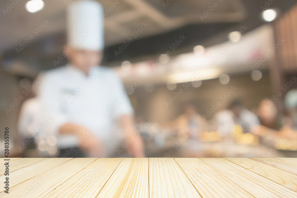 Empty wood table top with chef cooking in restaurant kitchen blurred ...