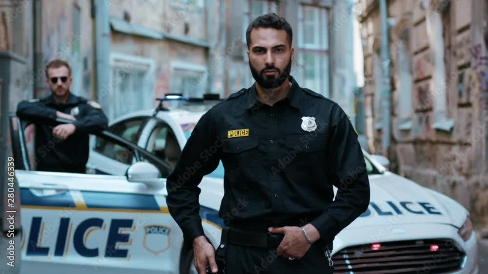Face young man cops stand near patrol car look at camera serious ...