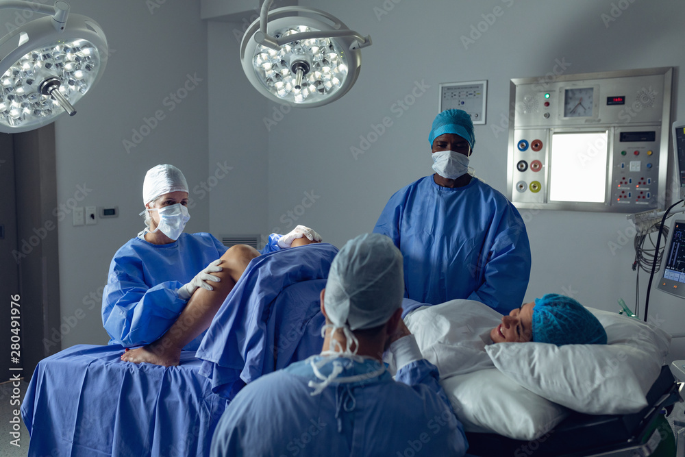 Surgeons examining pregnant woman during delivery while man holding her ...