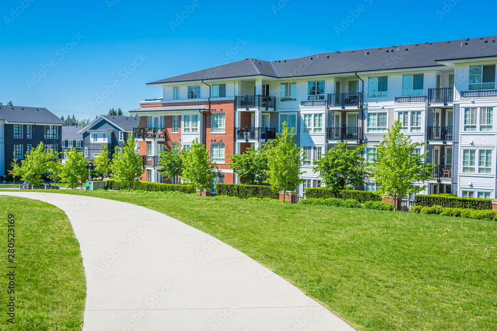 Concrete pathway across green lawn in front of residential condo ...