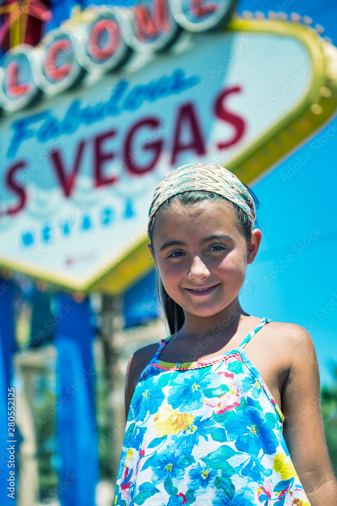Young girl standing happy under the famous Las Vegas sign on bright ...