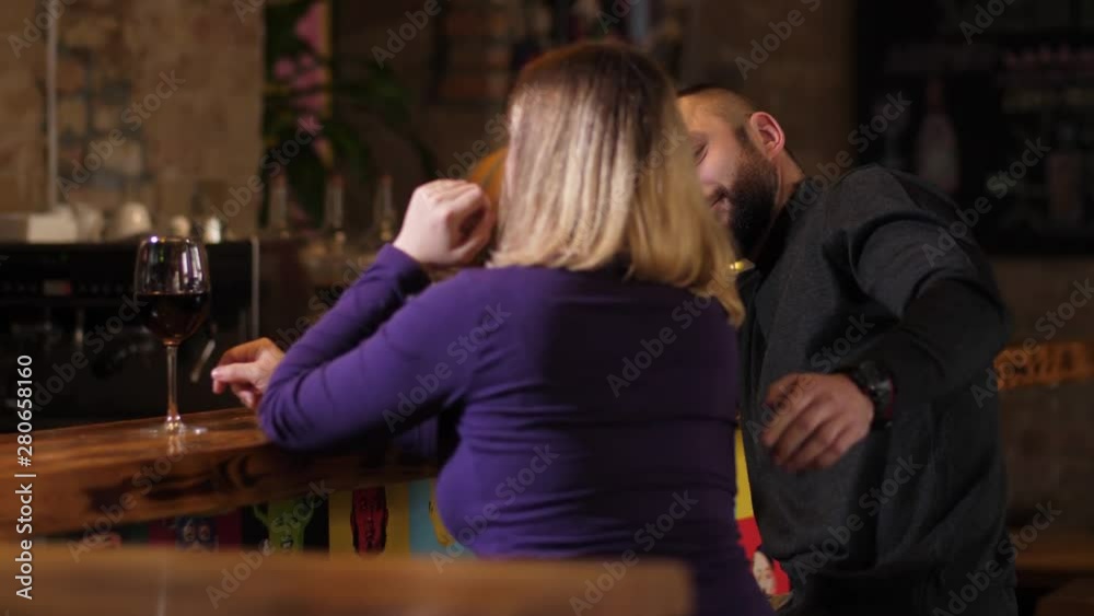 Rear view of male pestering female relaxing at bar counter touching her ...