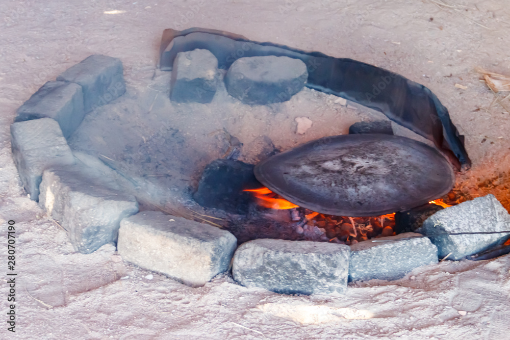 Traditional metal plate for making arabic pita bread cooking on fire in ...