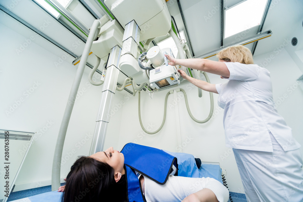 Radiologist and patient in a x-ray room. Classic ceiling-mounted x-ray ...