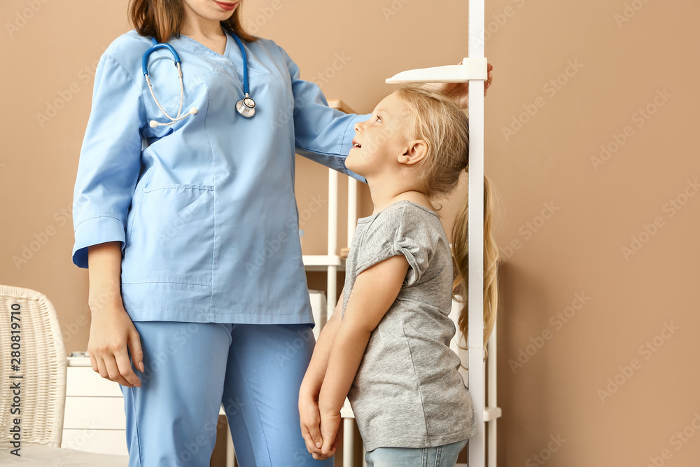 Female nurse measuring height of little girl in hospital Stock Photo ...