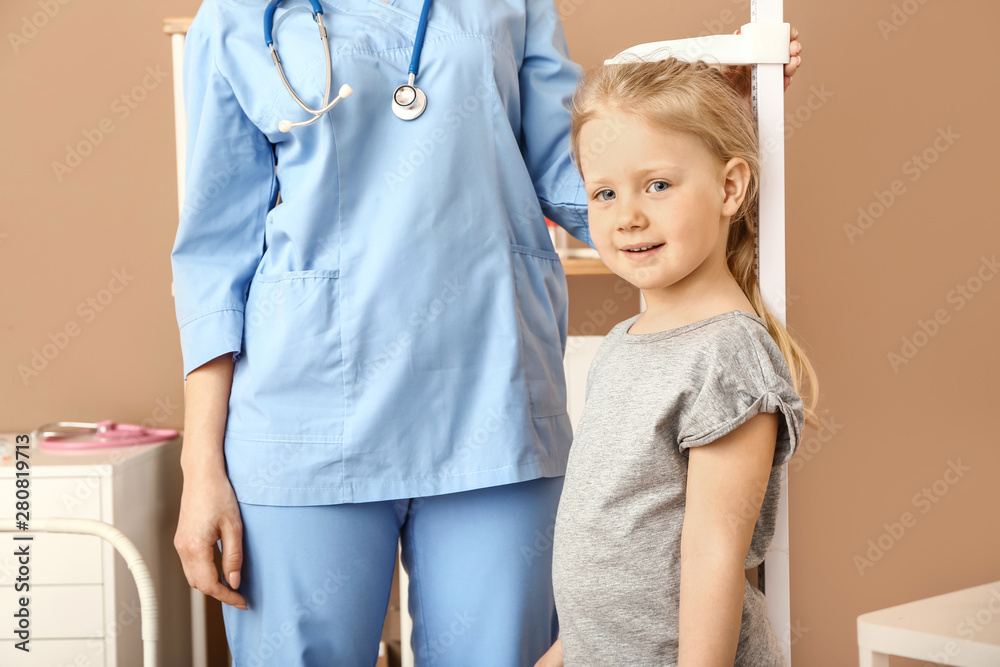 Female nurse measuring height of little girl in hospital Stock Photo ...