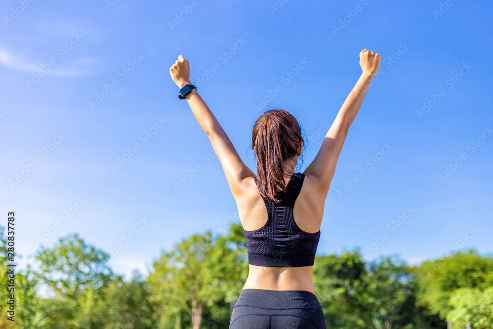 Happy young Asian woman raising up her arms cheerfully after complete ...