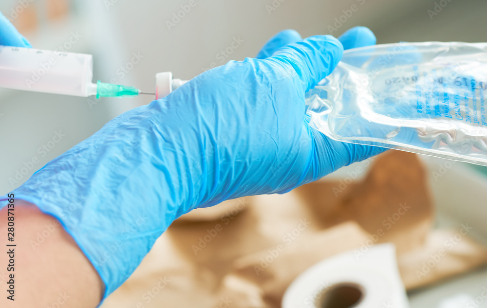 Nurse holding a medical syringe and solution for dropper in hands and ...