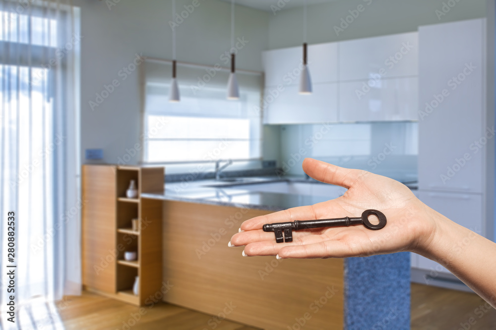 Business woman's hand holding key on blurry kitchen interior background ...