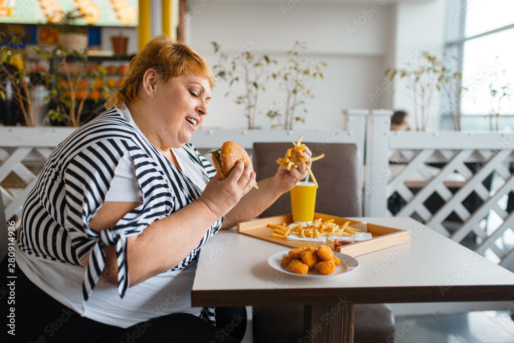 Fat woman eating high calorie food in restaurant Stock Photo | Adobe Stock