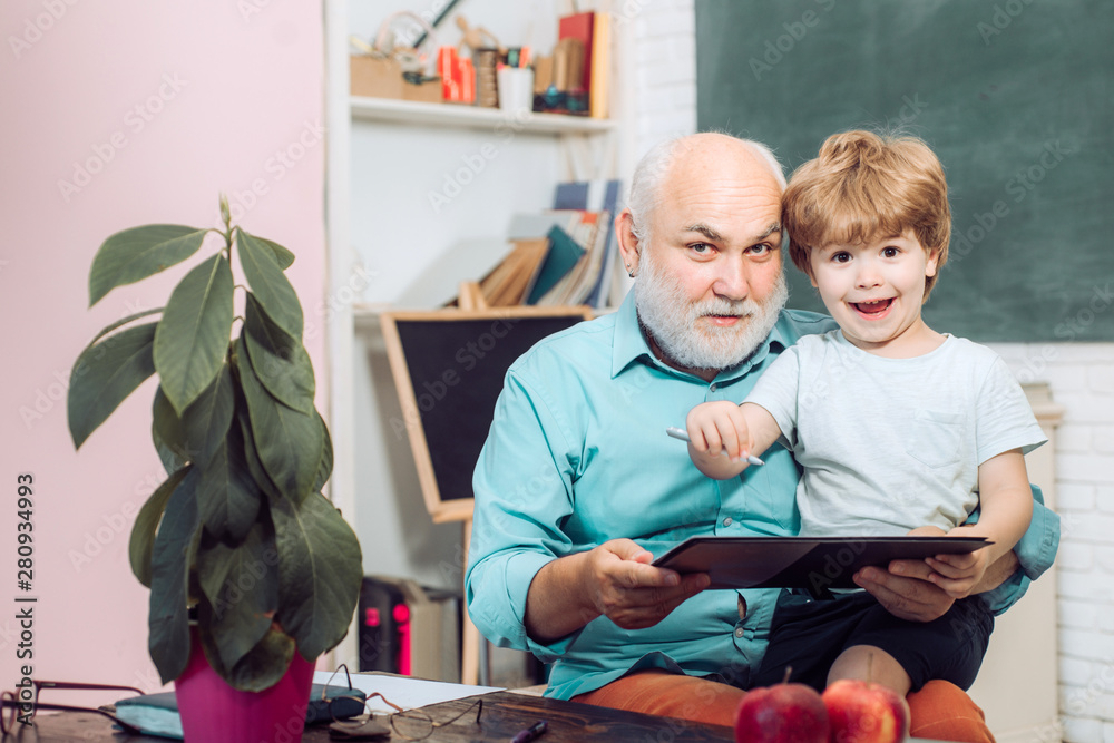 Cute little preschool kid boy with Grandfather in a classroom. A ...