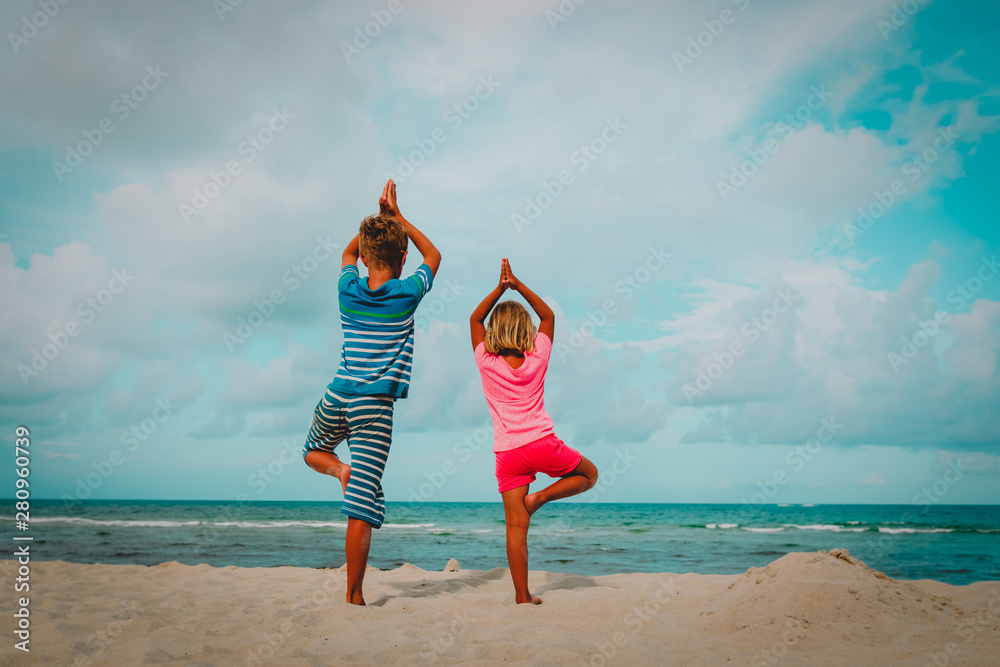 boy and girl doing yoga at beach, kids exercise at sea Stock Photo ...