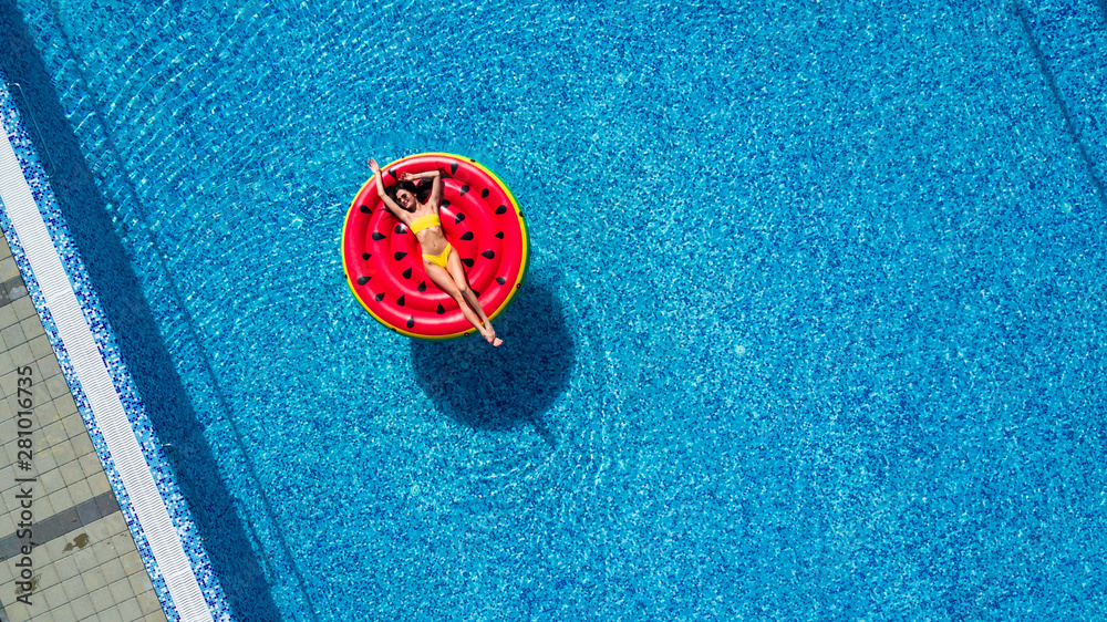 Aerial view of woman in bikini lying on a floating mattress in swimming ...