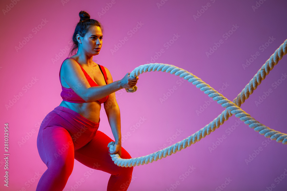 Young caucasian plus size female model's doing exercises on gradient ...