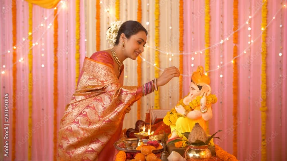 Cheerful Young Indian lady putting tilak on Lord Ganesh idol while ...