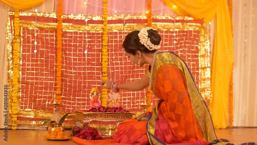 Beautiful Indian woman applying tika to Hindu God's idols and bowing ...
