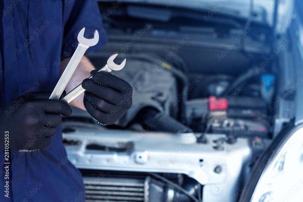 Repairman is repairing car at service station. Closeup mechanic hands ...