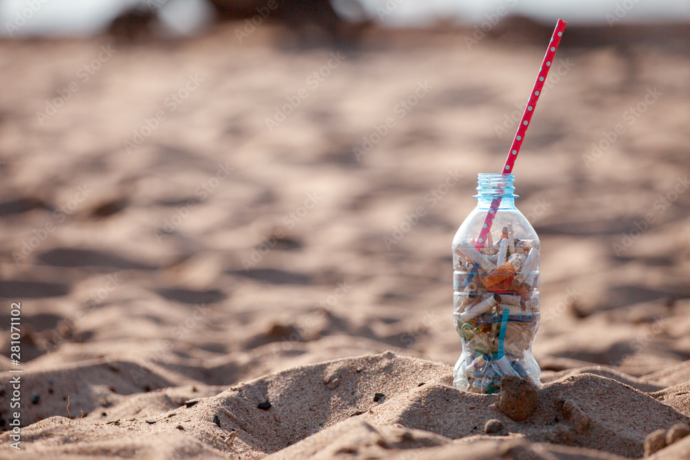 Cocktail with garbage and straw on clean beach. Plastic ocean pollution ...