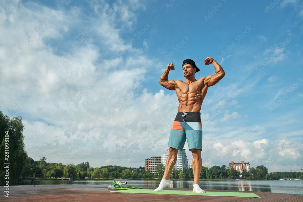 Strong man posing, showing his muscles. Stock Photo | Adobe Stock