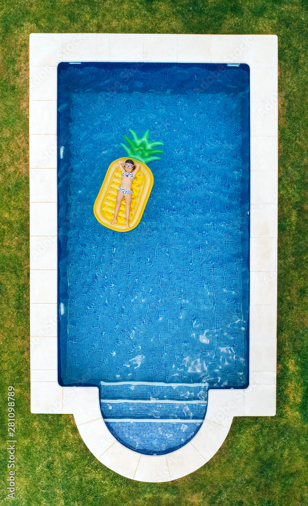 Little girl lying on a pineapple-shaped float in a swimming pool Stock ...
