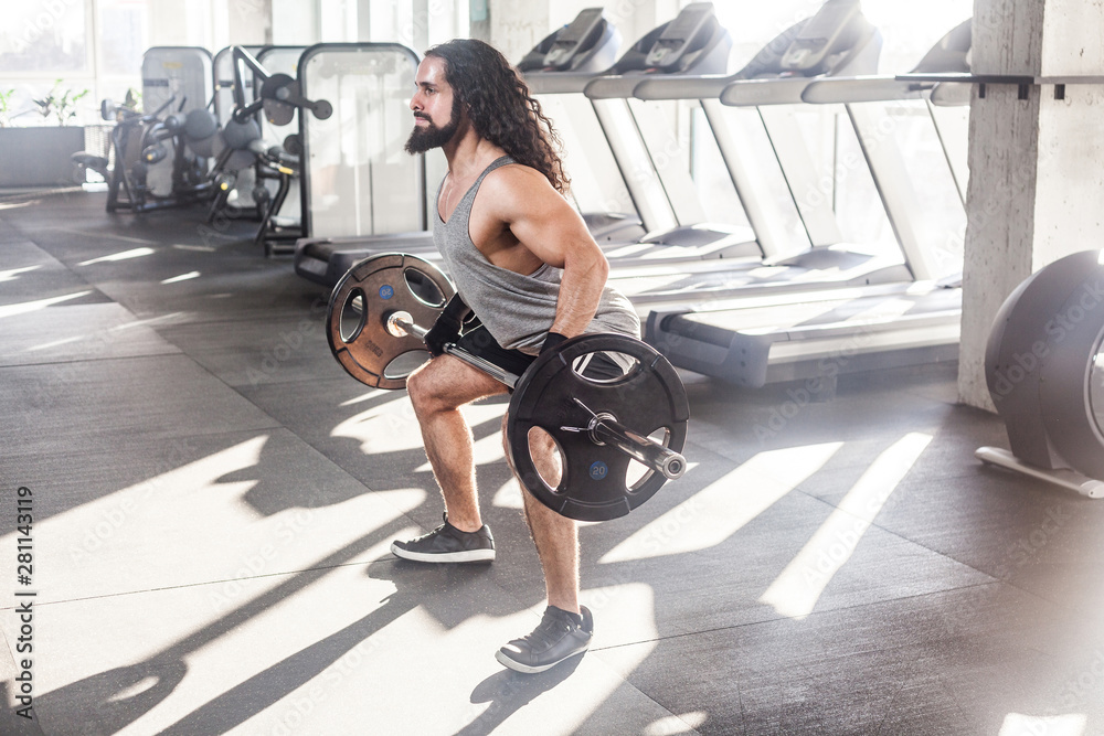 Side view portrait of young adult bodybuilder with long curly hair are ...