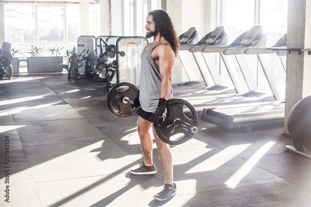 Side view portrait of young adult bodybuilder with long curly hair are ...
