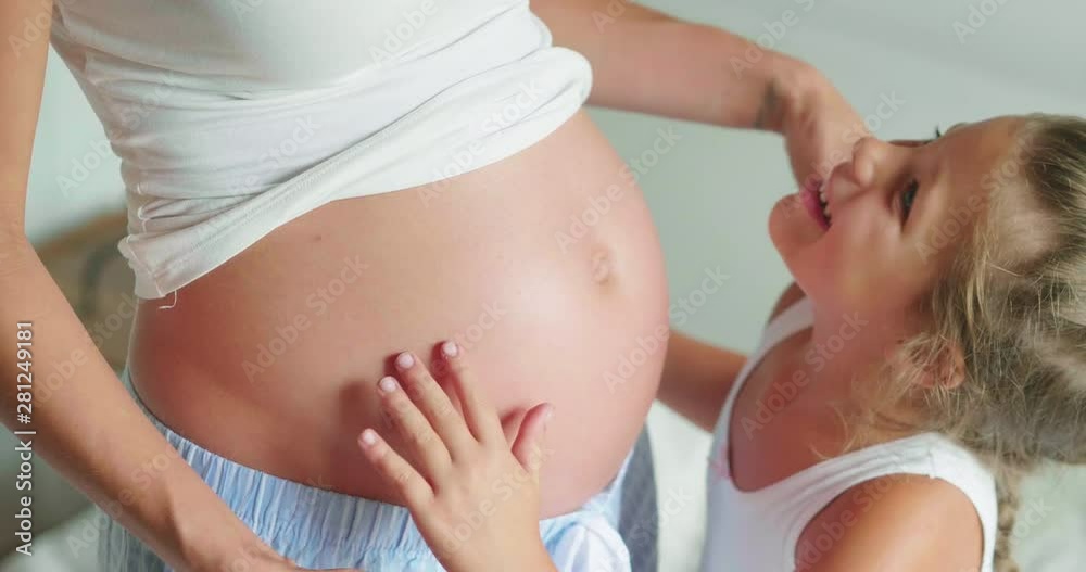 Vidéo Stock Authentic slow motion shot of a lovely little daughter is touching mother's pregnant ...