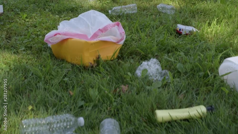 Trash and plastic bottles on grass. Garbage scattered in public park ...