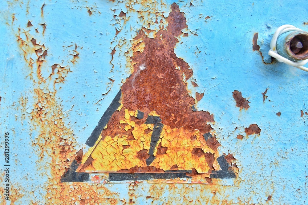Old electric shield with peeling blue paint and a yellow triangular ...