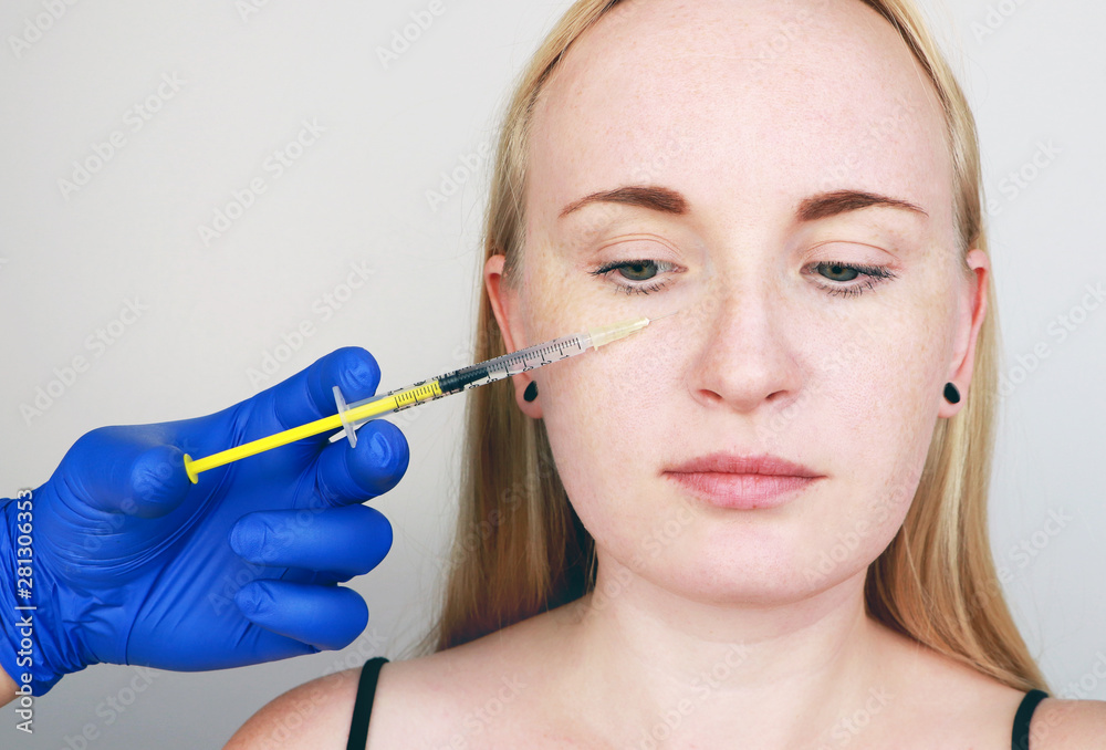 A cosmetologist carries out a procedure - an injection into the face of ...