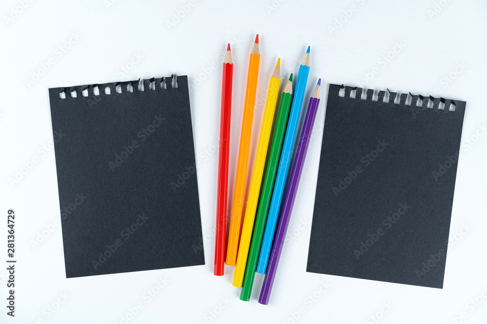 two black sheets notebook and lgbt colored pencils lie on white ...