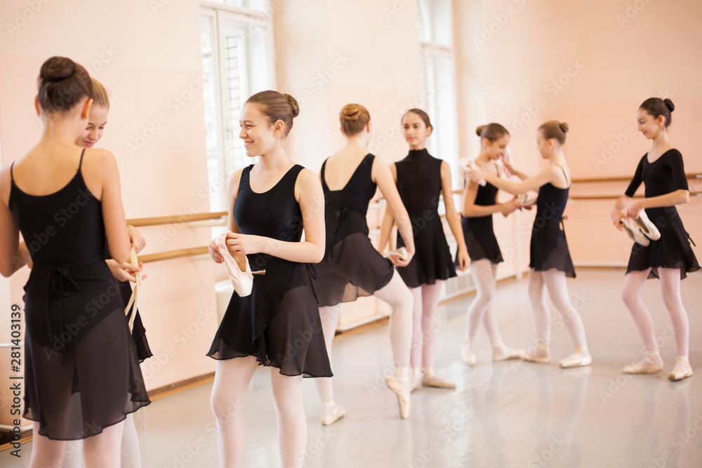 Medium group of teenage girls relaxing after a ballet class, talking to ...
