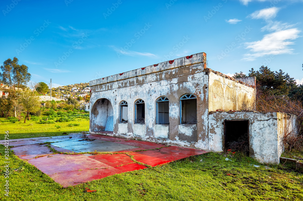 Exterior of an abandoned old white concrete single story house in a ...