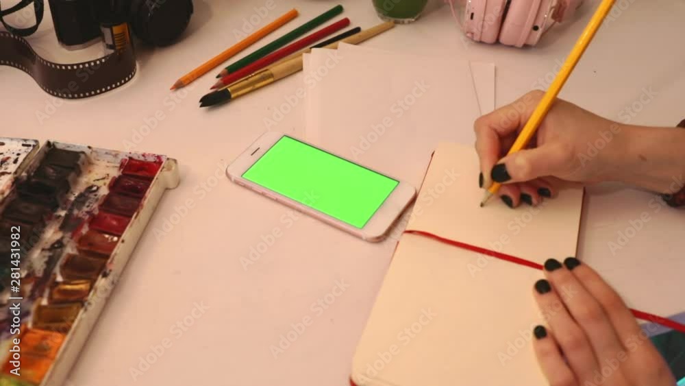 student painting from smartphone on table with art objects watercolor ...