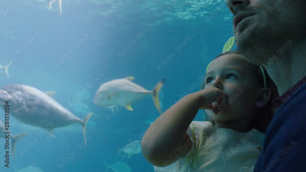happy girl with father at aquarium looking at fish swimming in tank ...