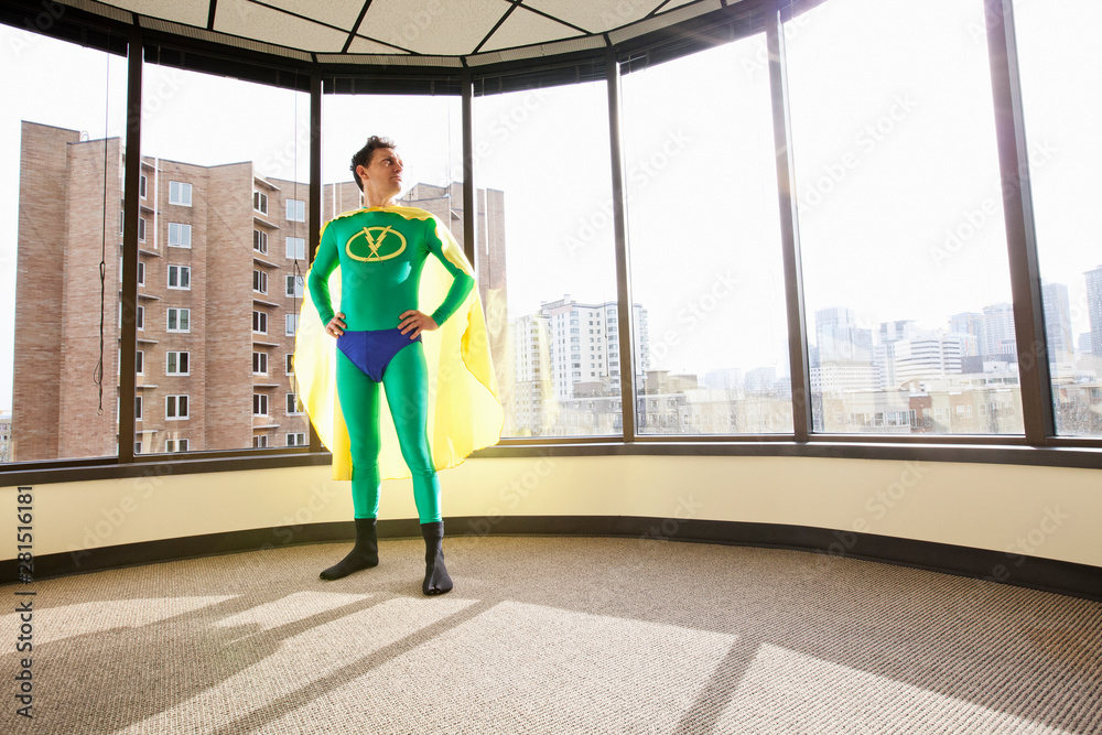 Businessman in super hero costume looking through window Stock Photo ...