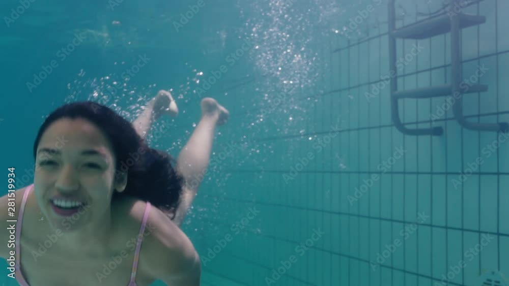 beautiful woman swimming underwater in pool smiling waving hand ...