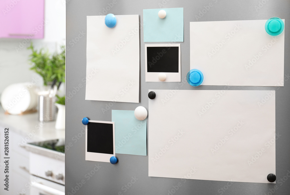 Sheets of paper and photos with magnets on refrigerator door indoors ...