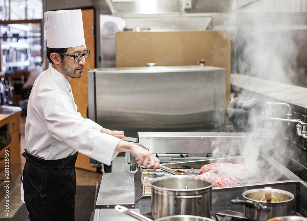 Chef grilling meat on grill in commercial kitchen Stock Photo | Adobe Stock